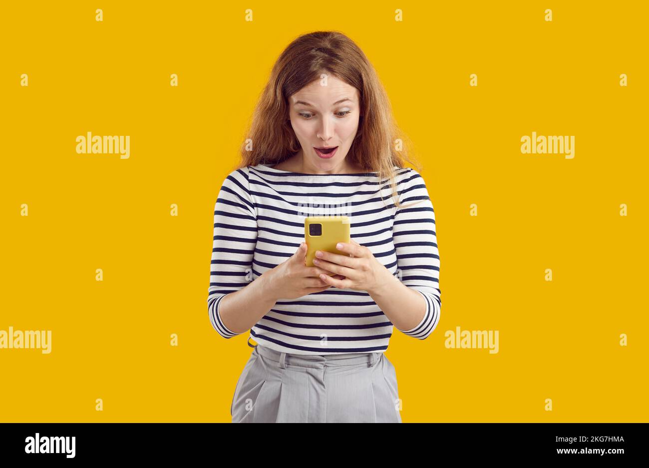 Young woman looking at her mobile phone with happy excited surprised ...