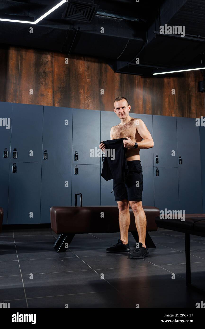 A young man changes clothes in a room in the gym before training Stock ...
