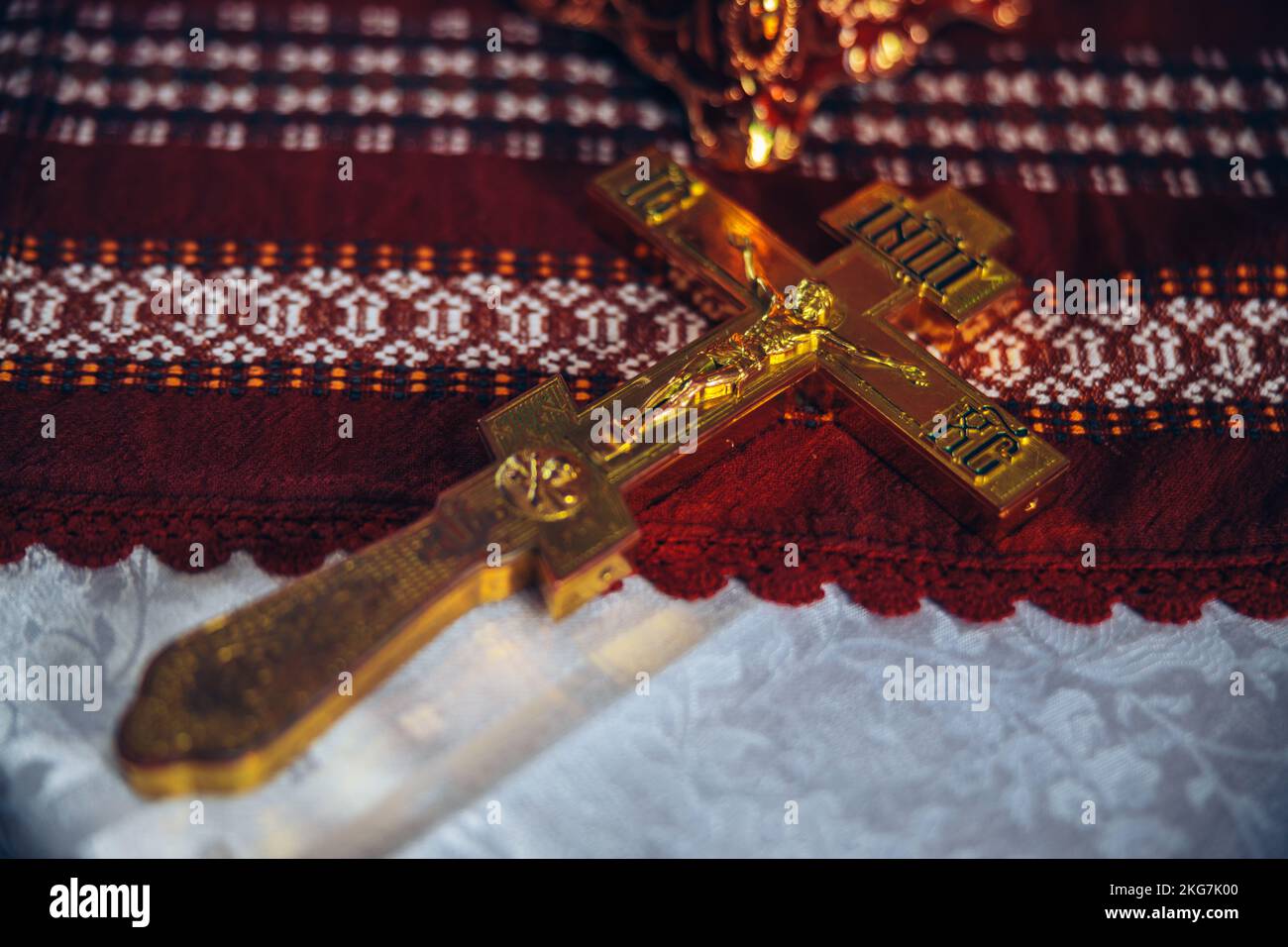 Golden cross on a red and white cover background in the holy church for a child's orthodox ...