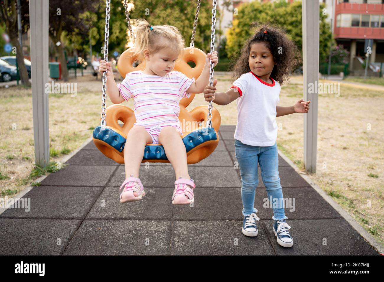 Two cute interracial friends playing together outside Stock Photo - Alamy