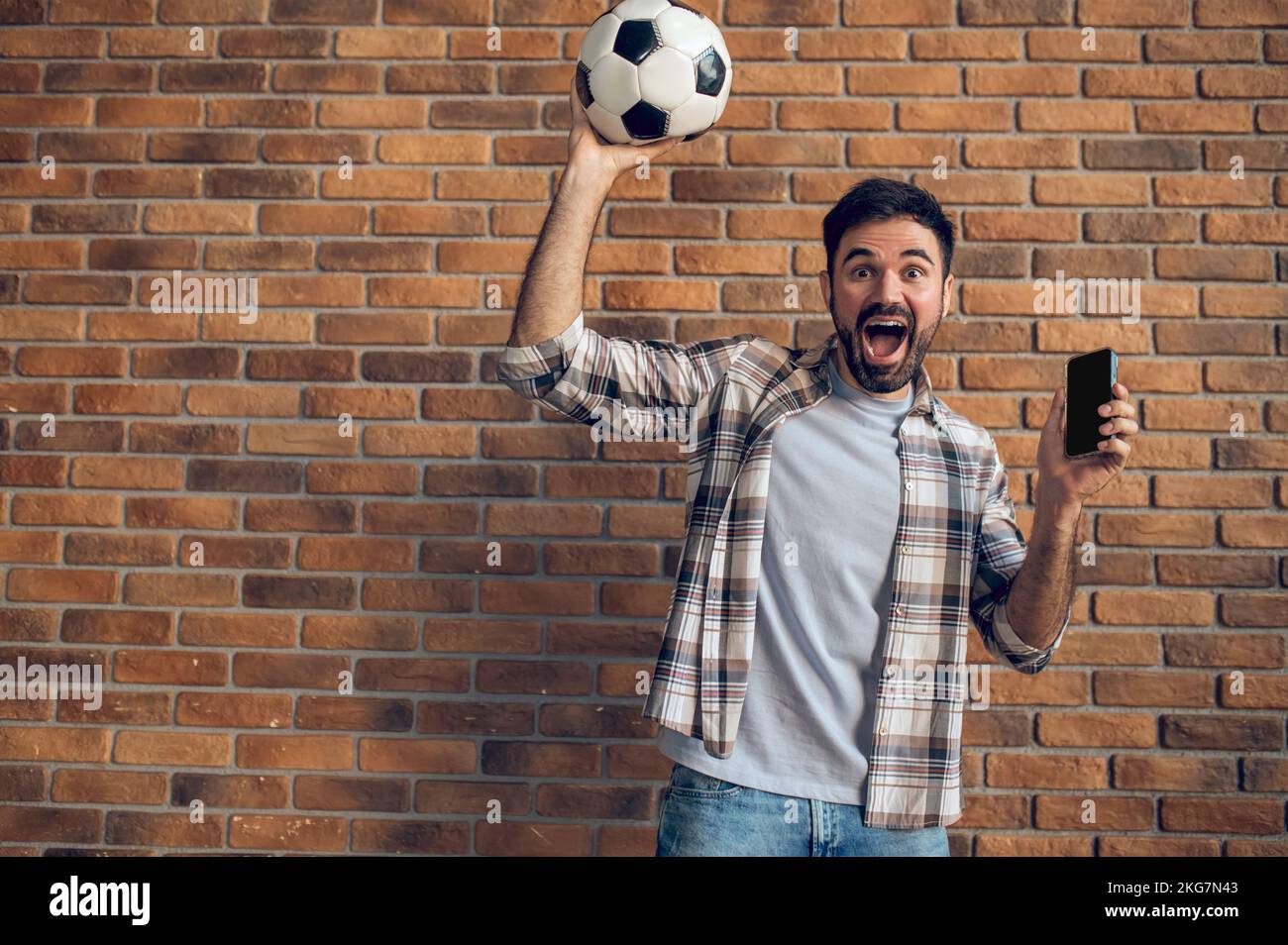 Screaming young fan holding his football in the raised hand Stock Photo ...