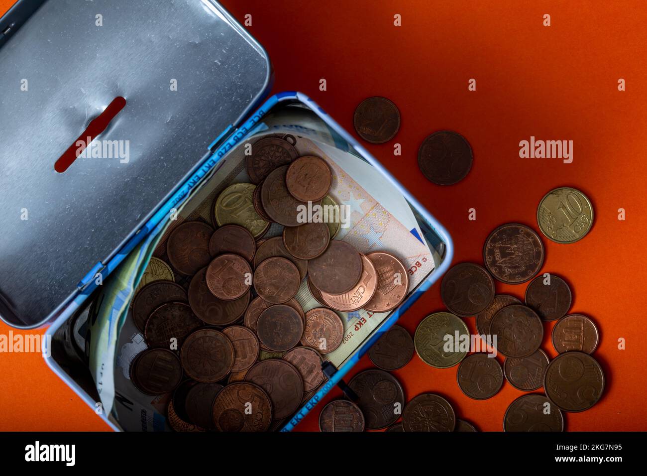 Money box with coins and banknotes on orange background Stock Photo - Alamy