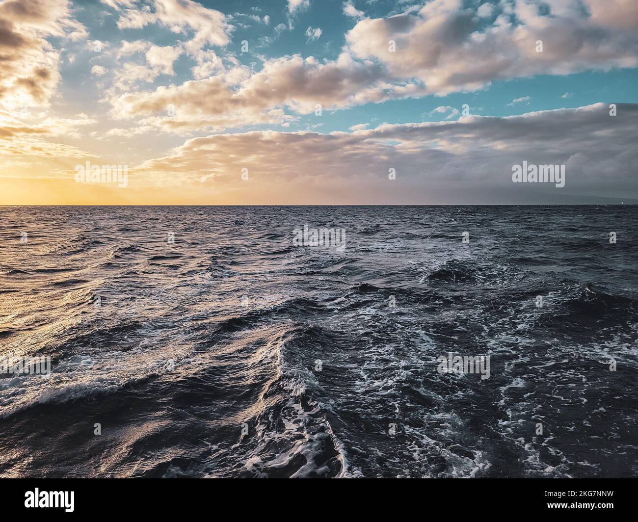 A scenic shot of turbulent waves of the blue sea under the clouds and ...
