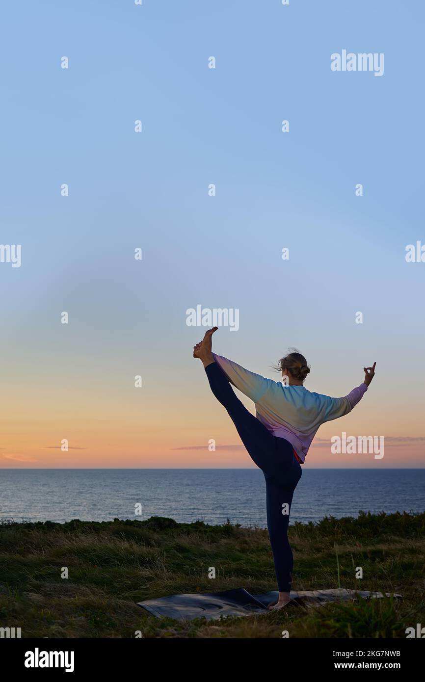 healthy woman in yoga class doing exercise outdoor. vertical image with ...