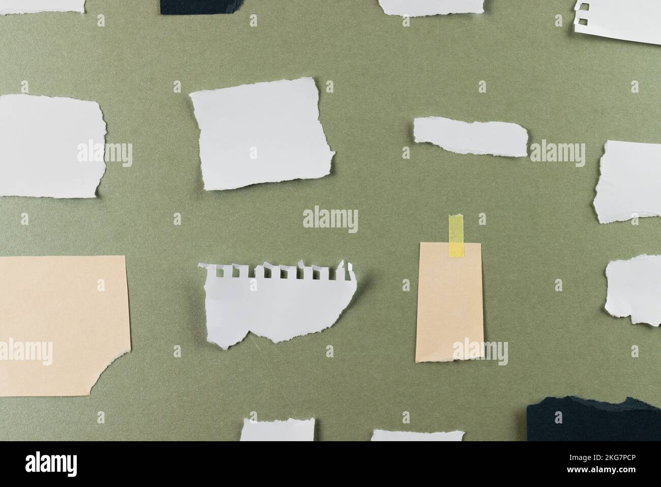 Ripped up pieces of black and white paper with copy space on green ...