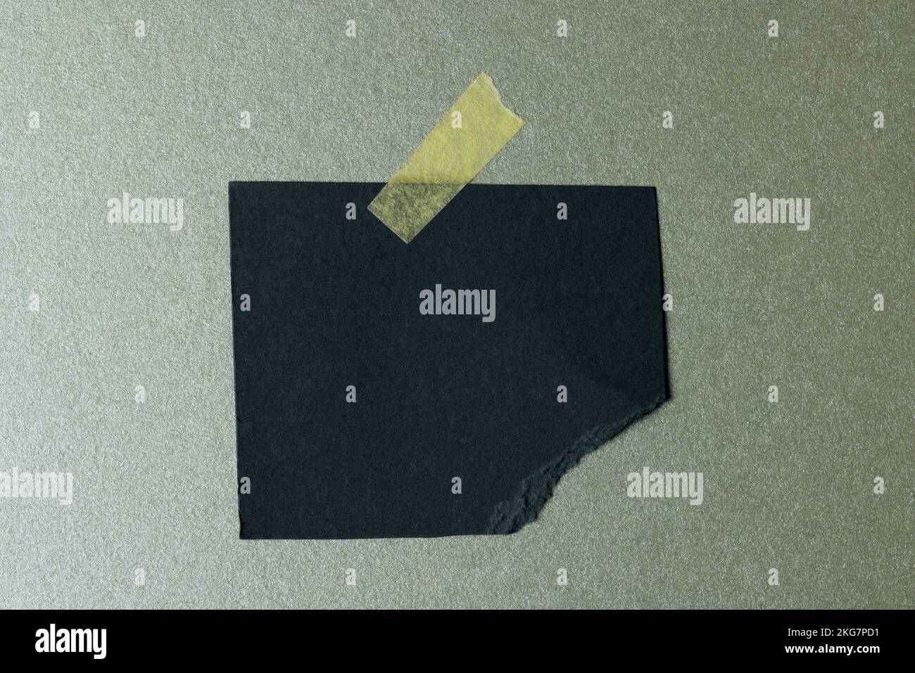 Ripped up piece of black paper with copy space on green background ...