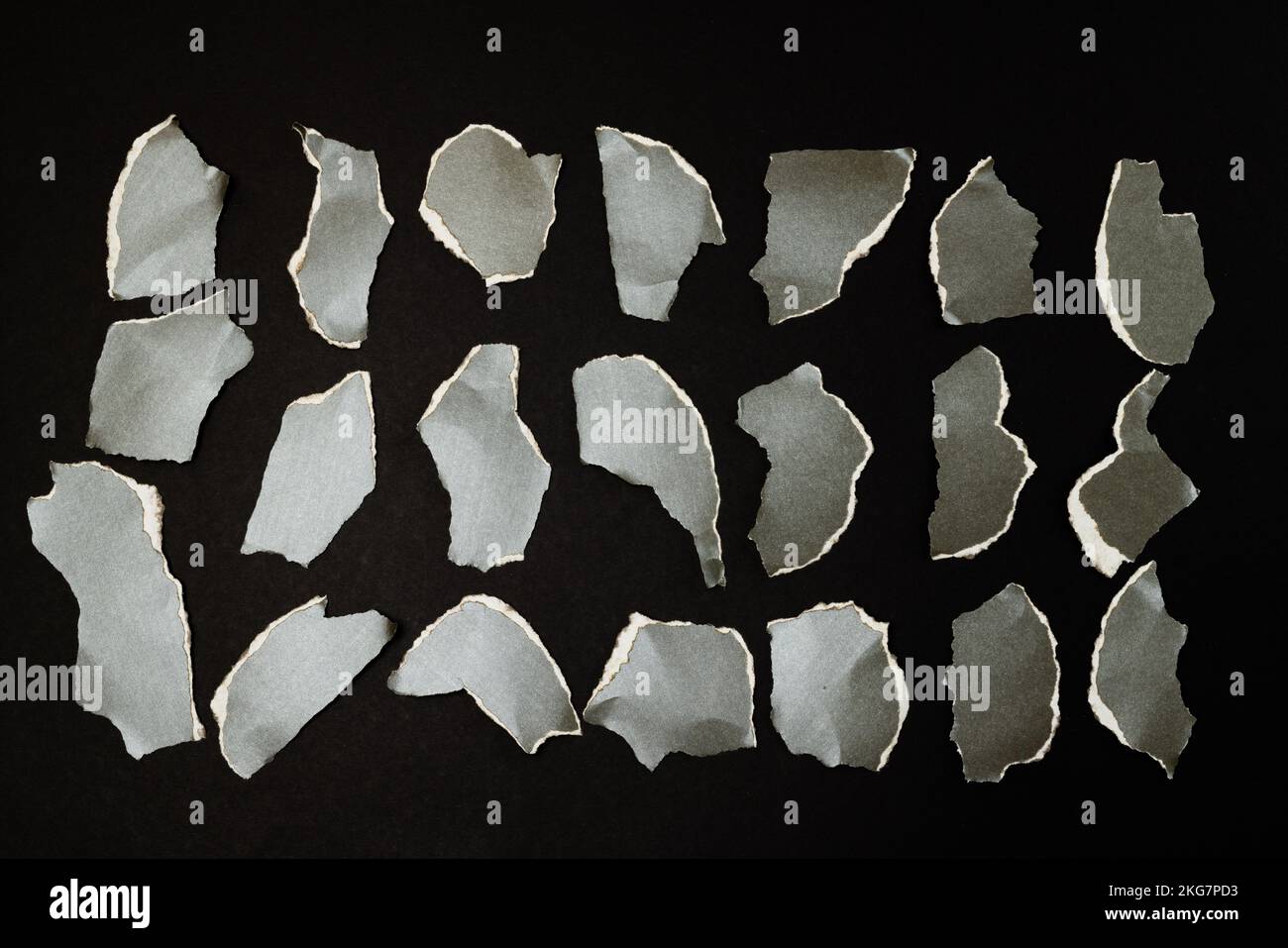 Ripped up pieces of gray paper with copy space on black background ...