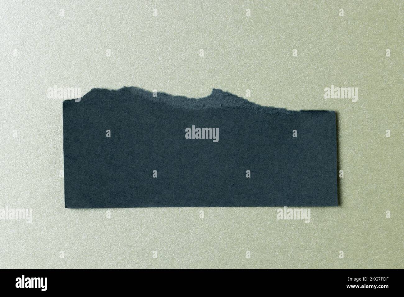 Ripped up piece of black paper with copy space on cardboard background ...