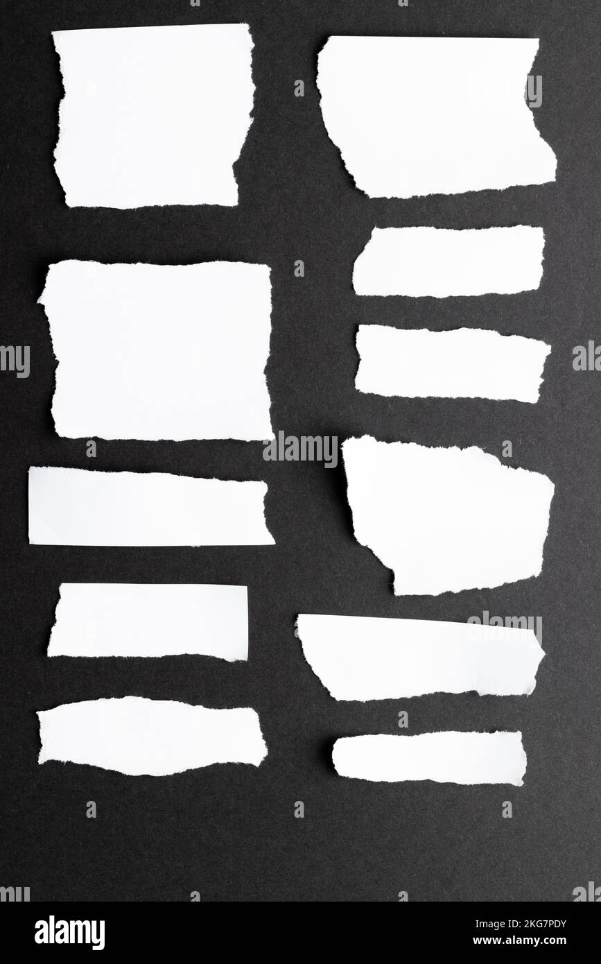 Ripped up pieces of white paper with copy space on black background ...