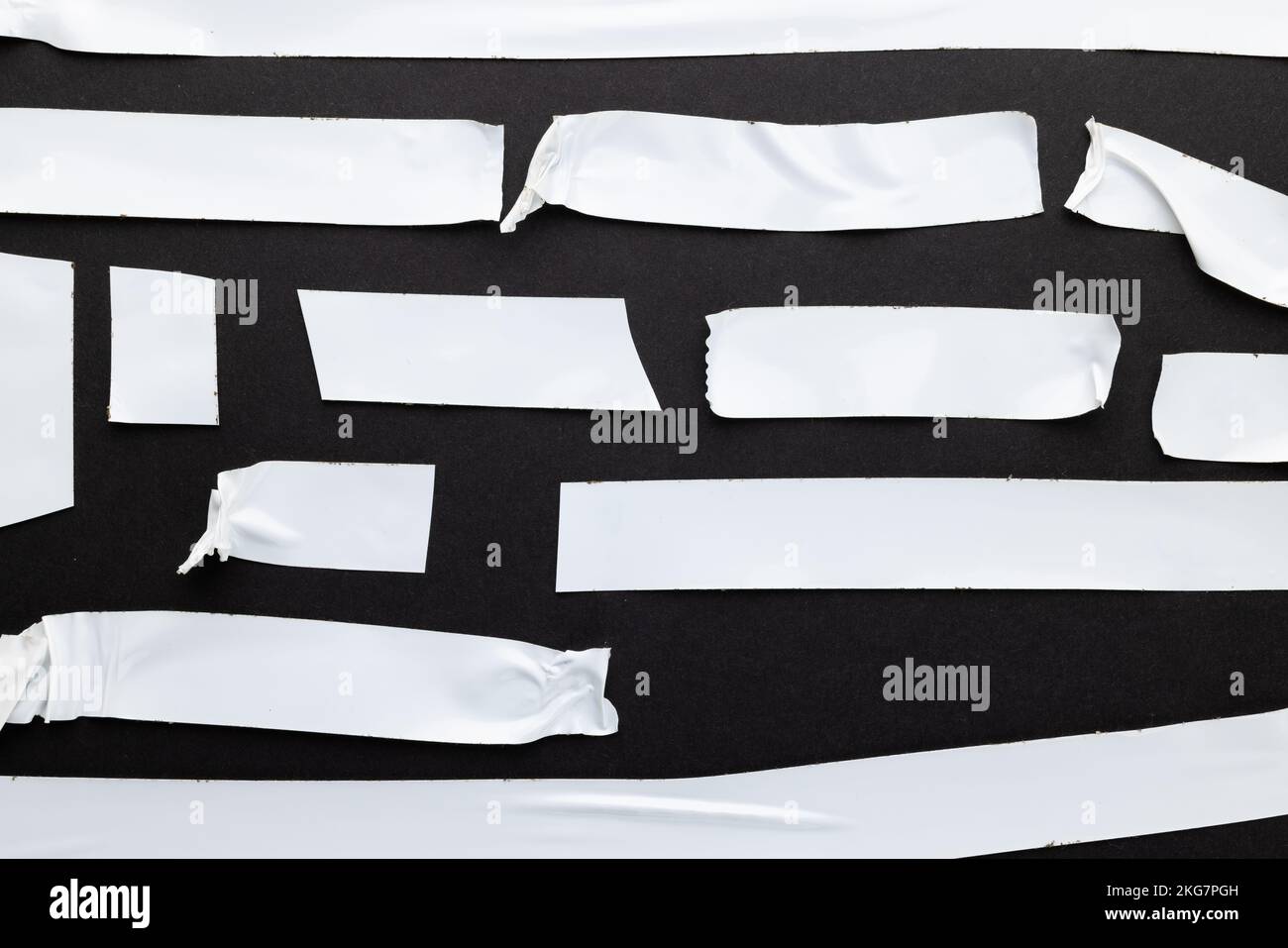 Ripped up pieces of white tape with copy space on black background ...