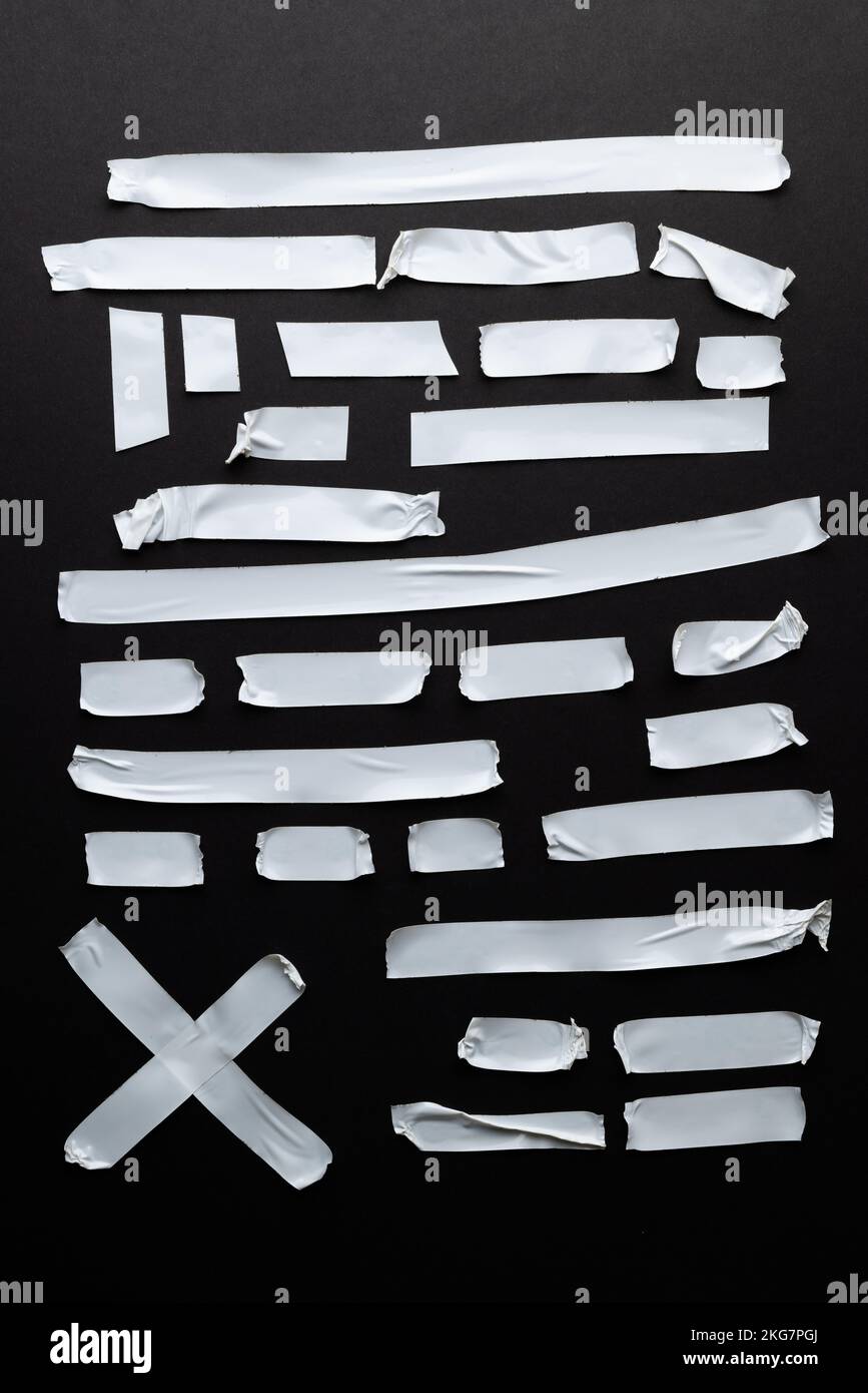 Ripped up pieces of white tape with copy space on black background ...