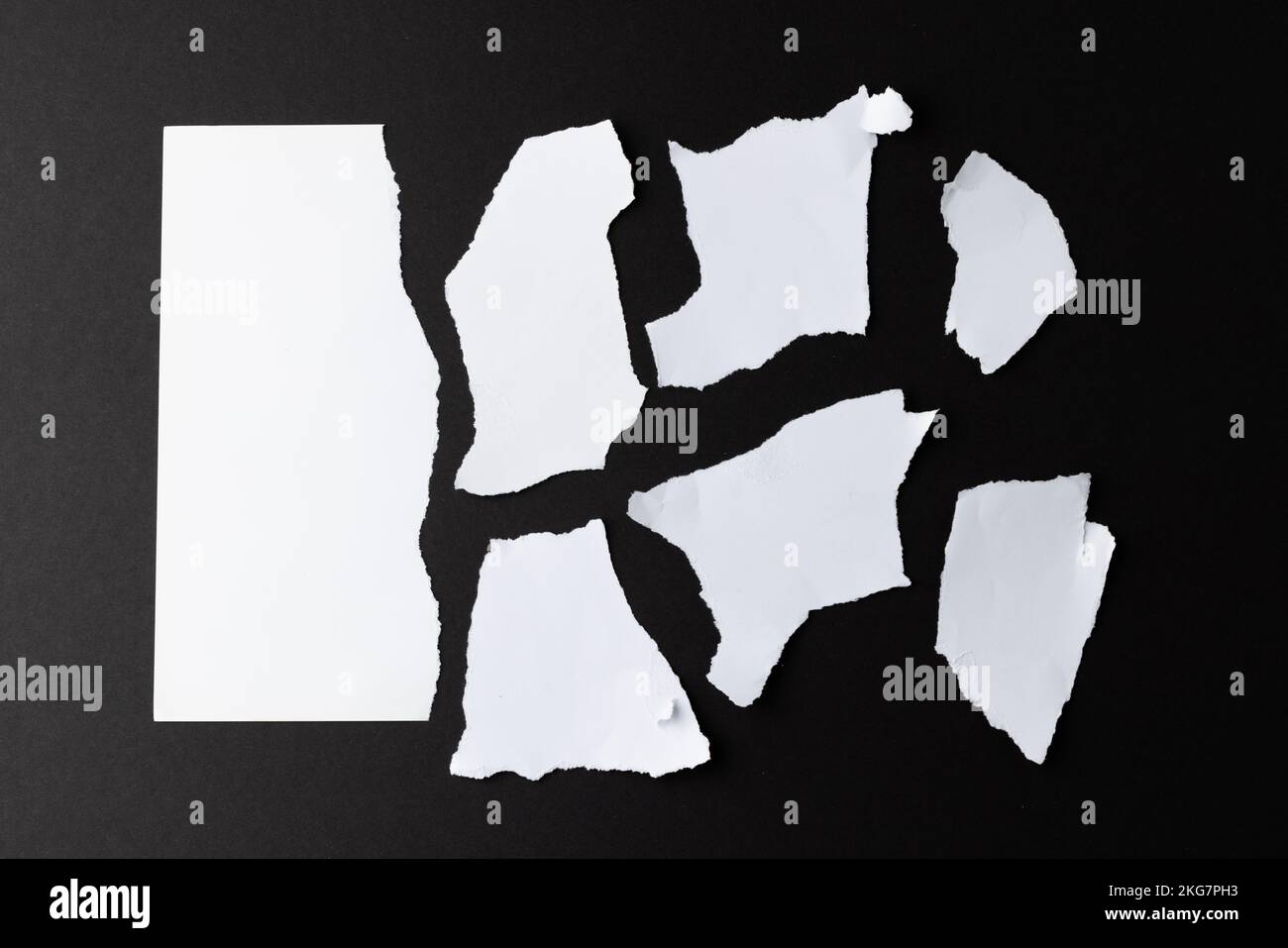 Ripped up pieces of white paper with copy space on black background ...