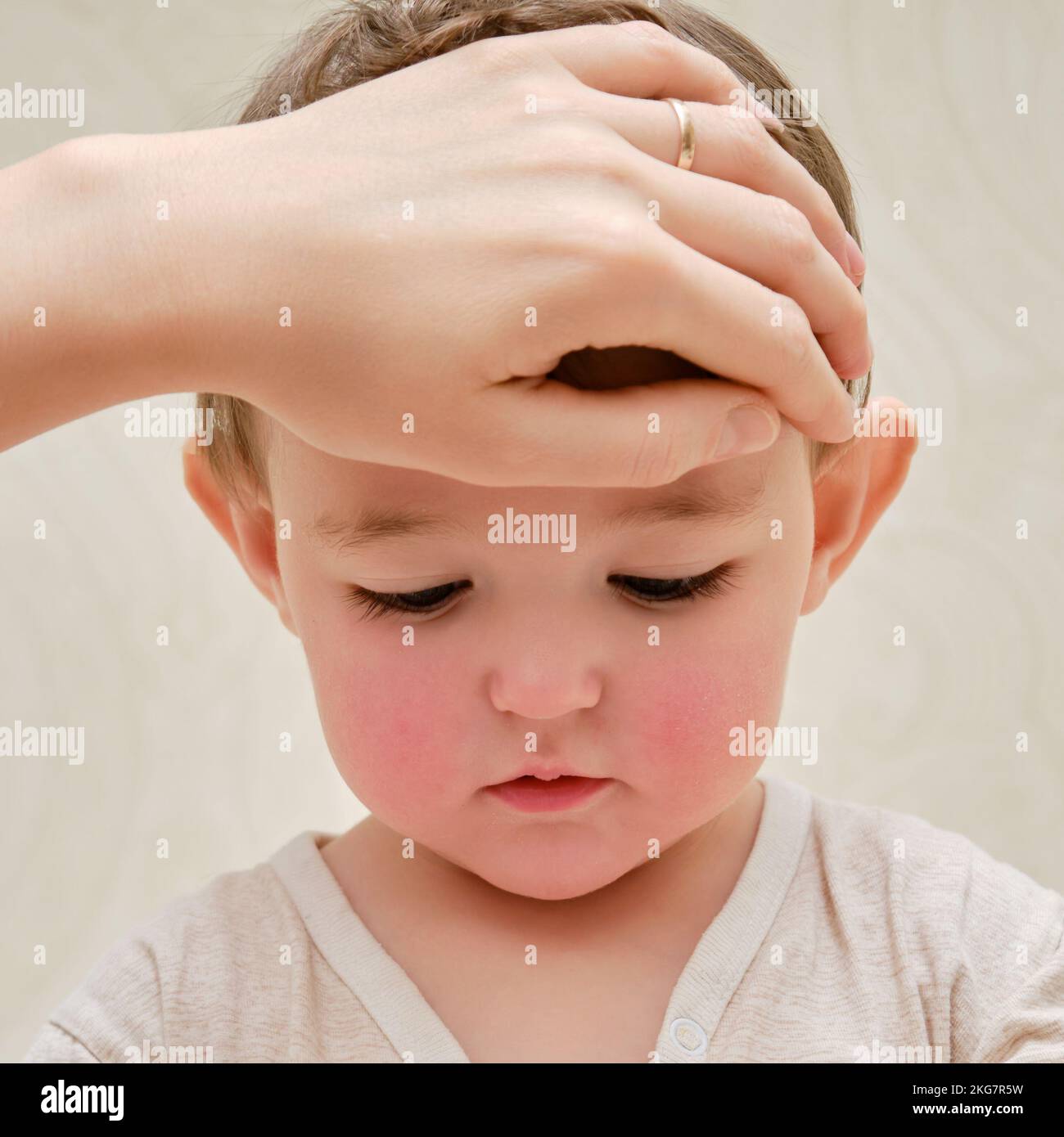 A mother woman measures the temperature of a ill toddler baby with her ...