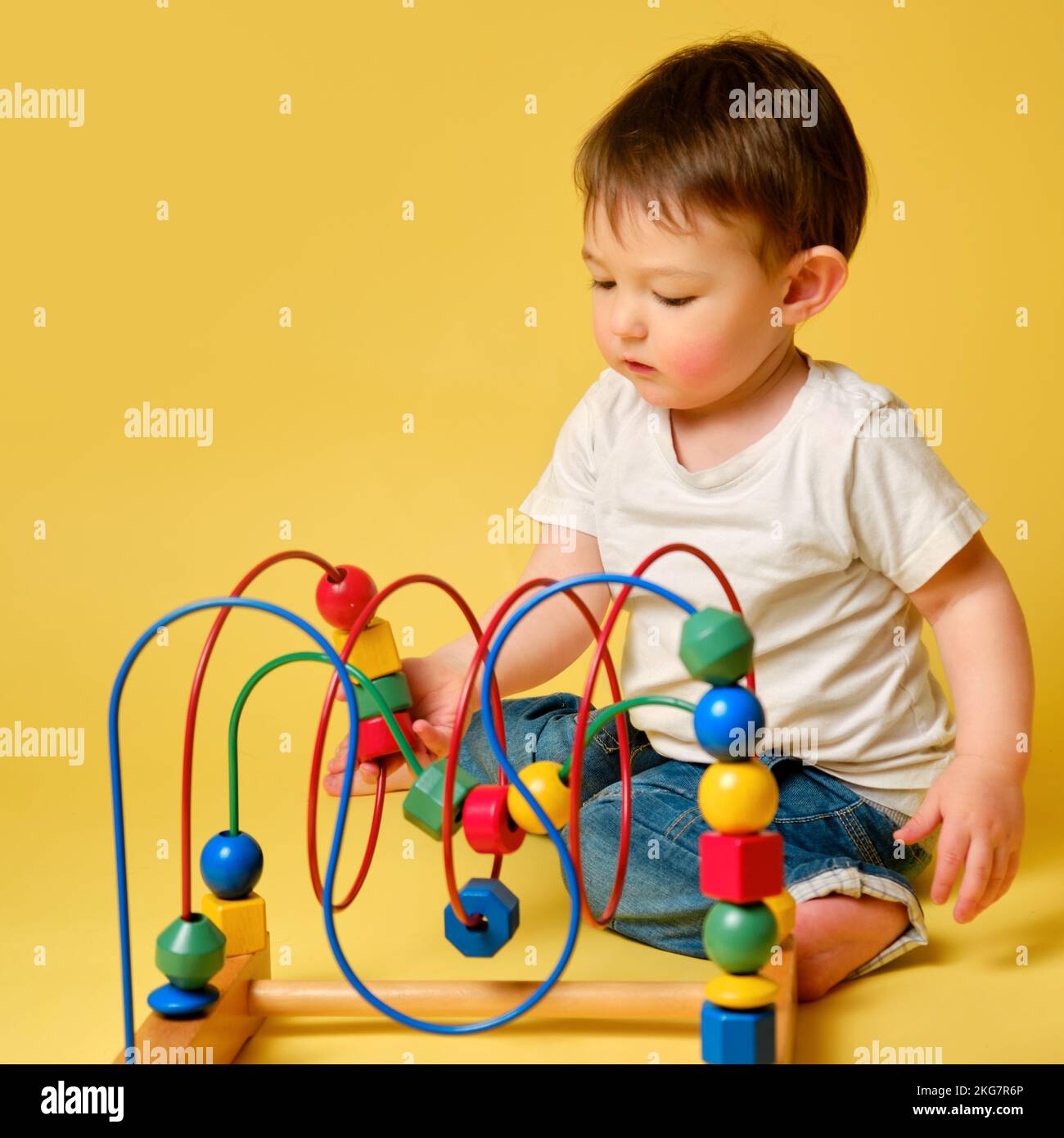Toddler baby is playing logic educational games on a studio yellow ...