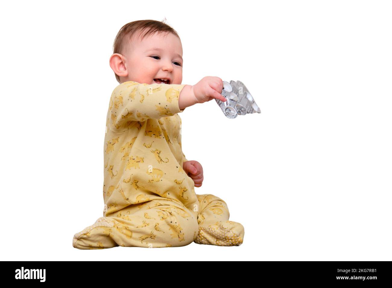 Toddler baby boy plays with medicines in a package while sitting on the ...
