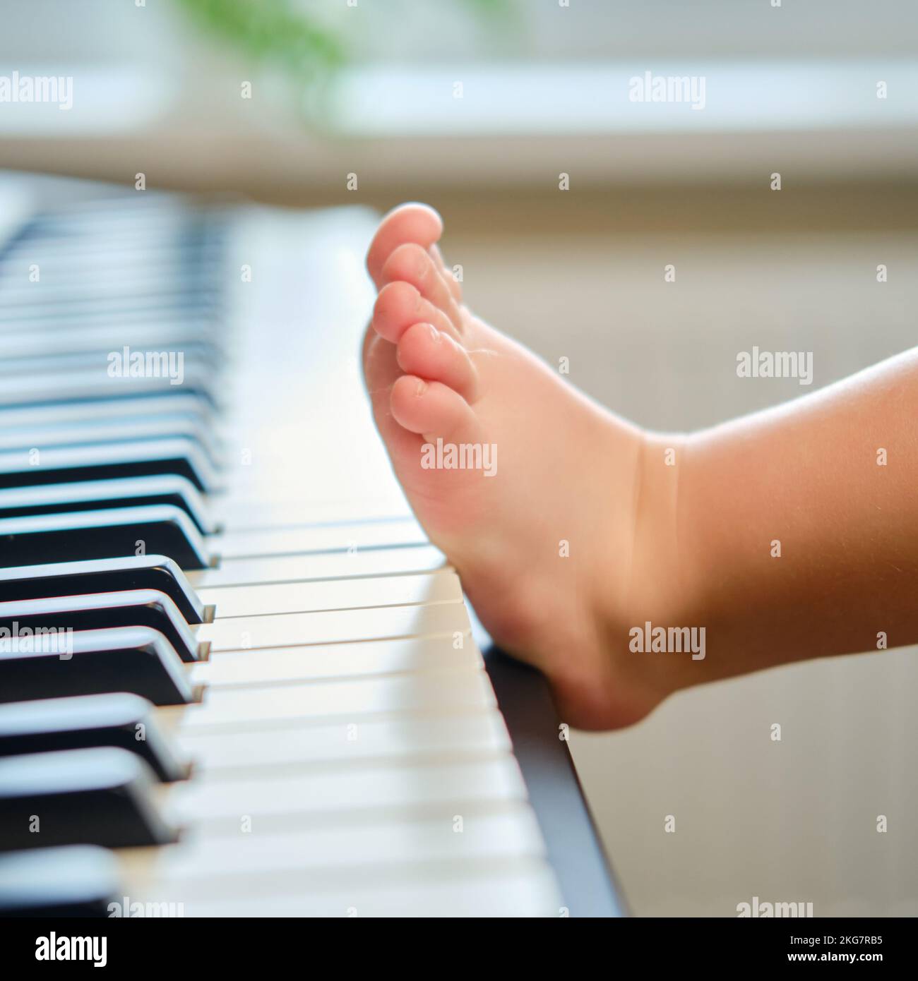 Toddler baby foot on electric piano keys, close-up. Child feet lie on ...