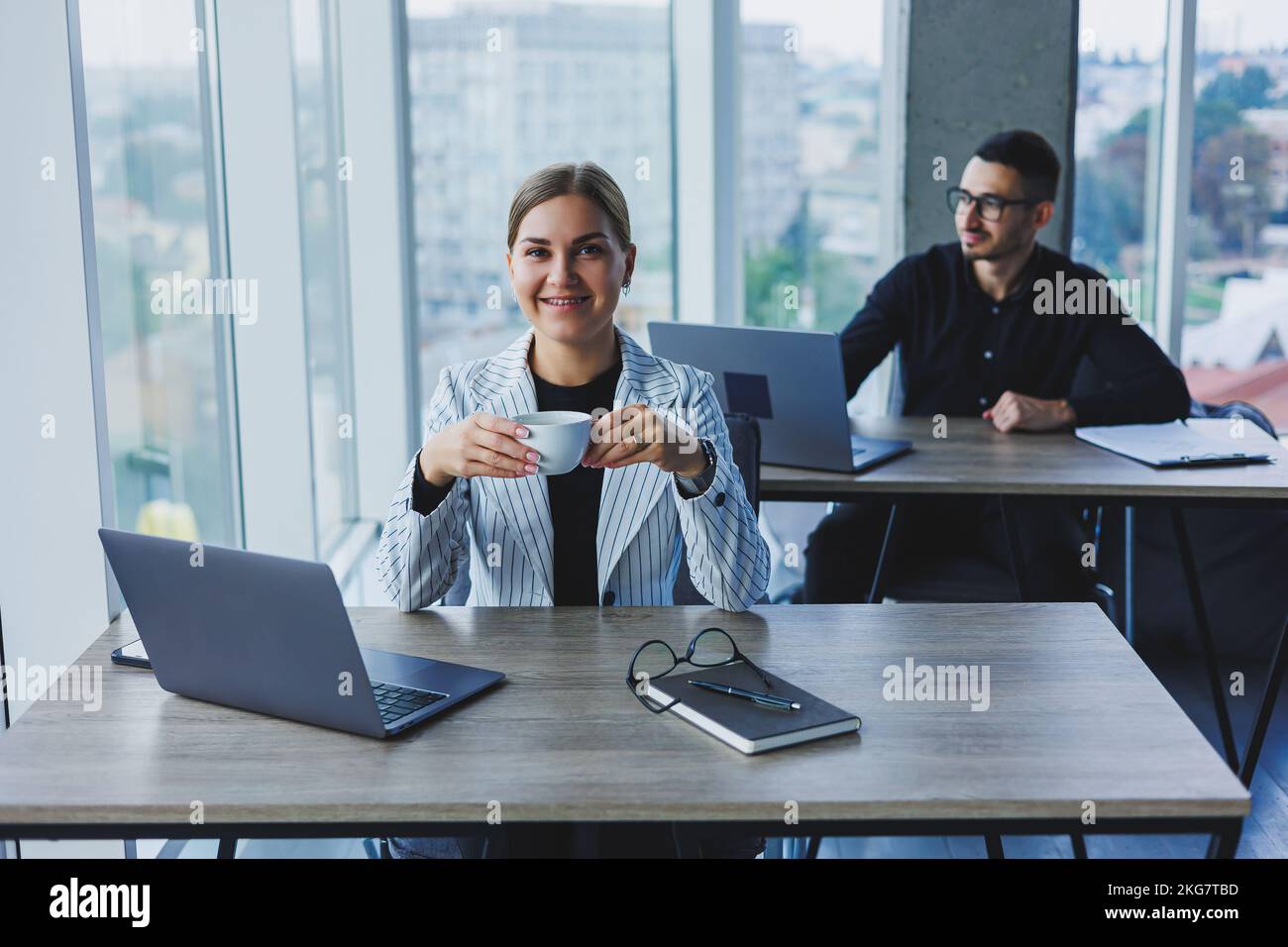 A female manager sits at a desk using a laptop in a modern office with ...