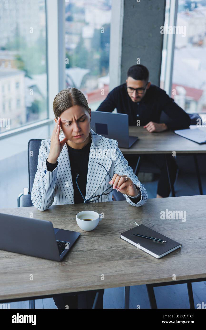 A female manager sits at a desk using a laptop in a modern office with ...
