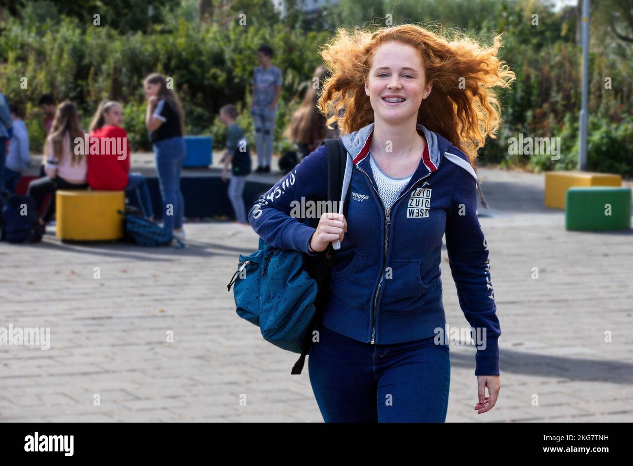 Secondary school student with red hair is walking on the school square ...