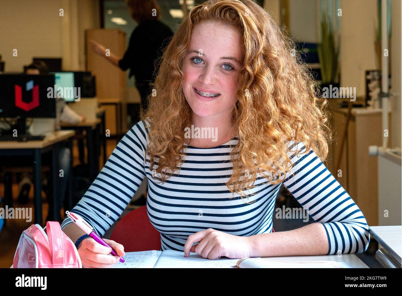 Student with red hair working in a classroom in a secondary school ...