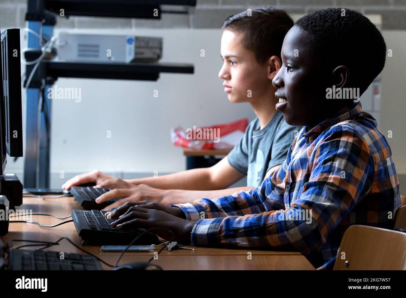 Two boys on a secondary school works with computer in a classroom ...