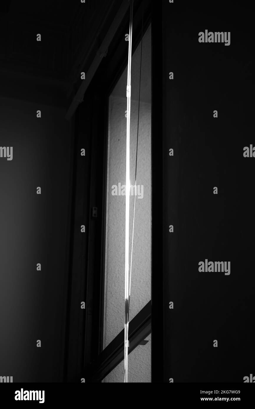 A vertical grayscale shot of the curtain batons reflecting the light ...