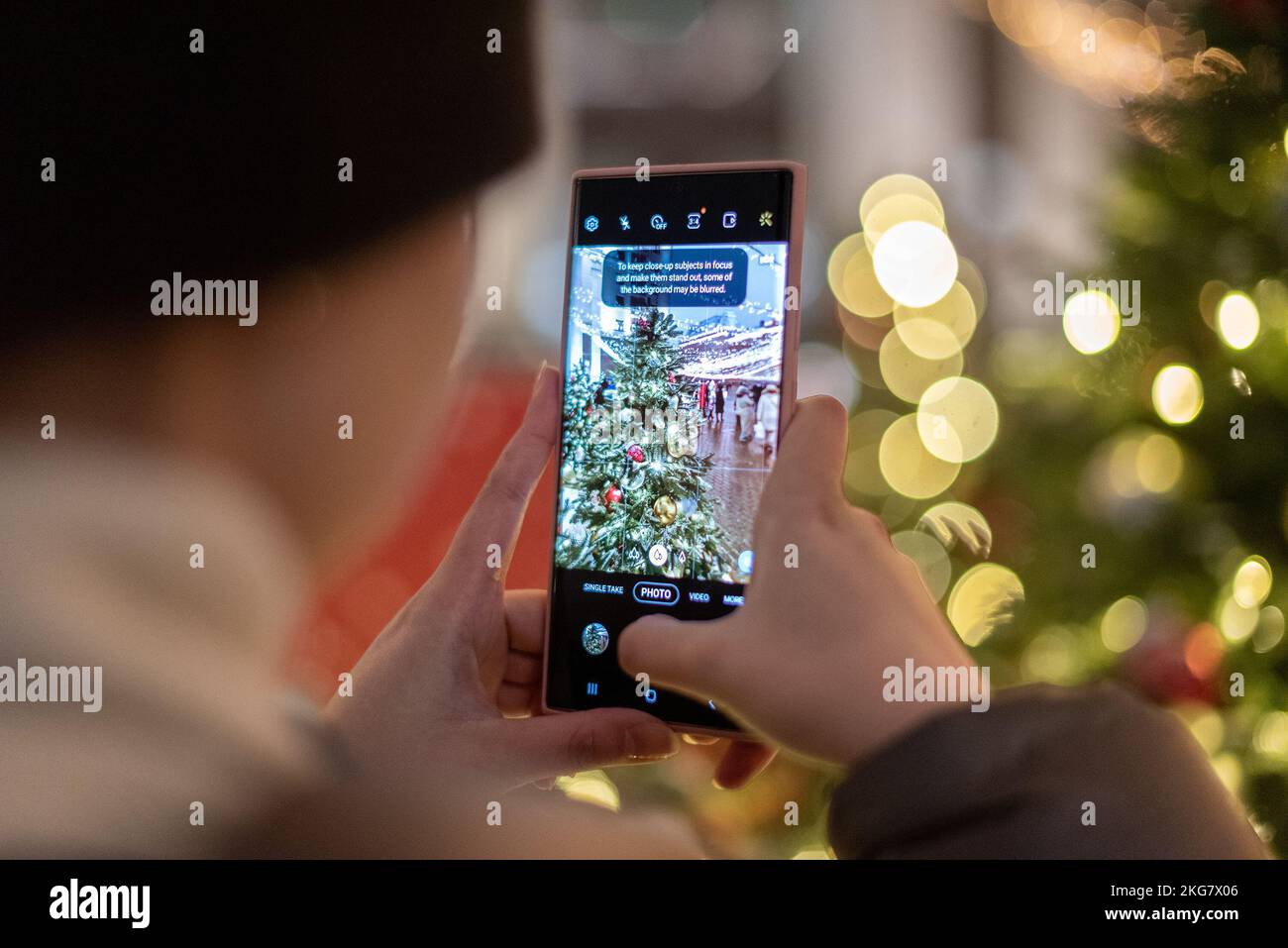 Girl photographs a Christmas tree, garlands and decorations on a ...