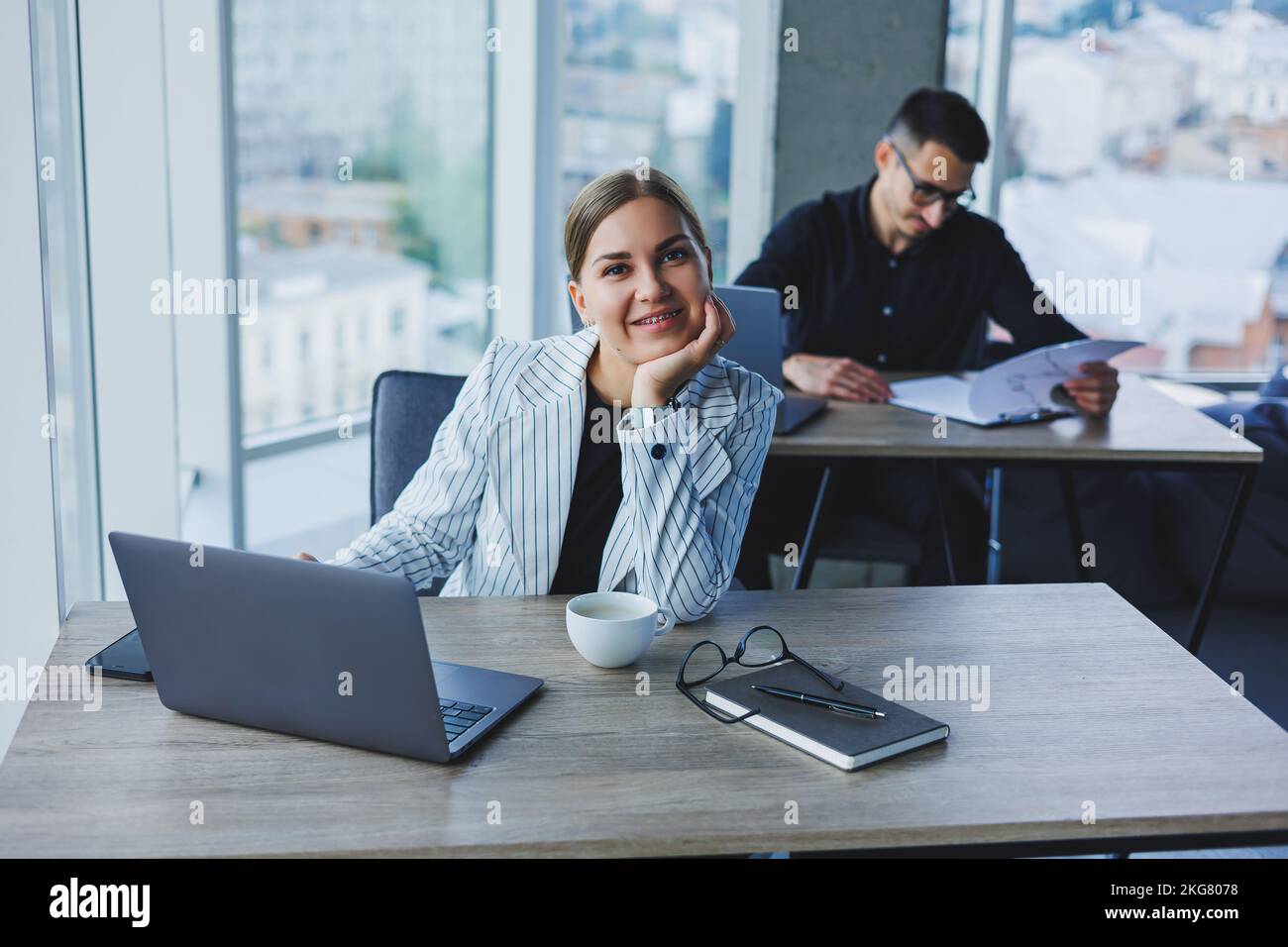 A female manager is sitting at a desk using a laptop in a modern office ...