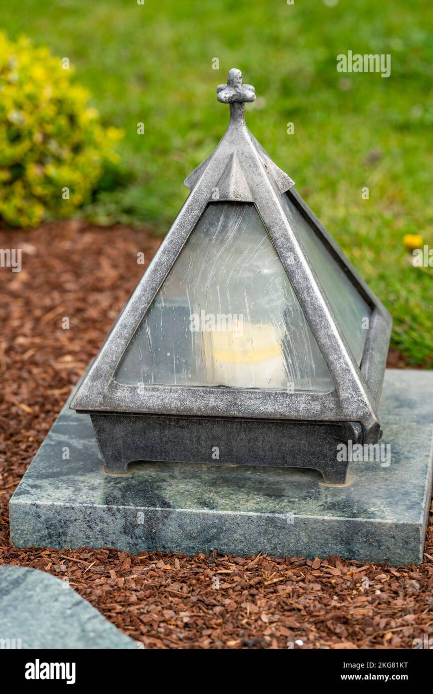 Grave light with burning candle on a grave with flowers Stock Photo - Alamy