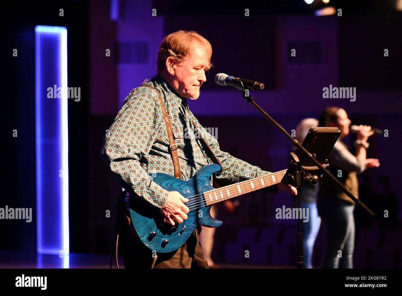 A closeup shot of an old man playing on a blue solo guitar in the ...