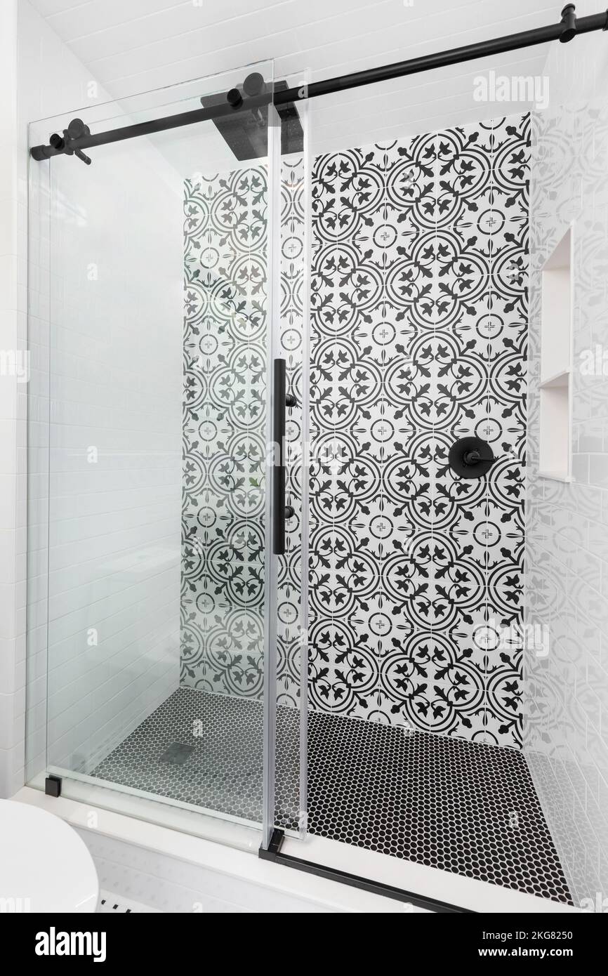 A shower with a black and white patterned tile on the wall, black ...