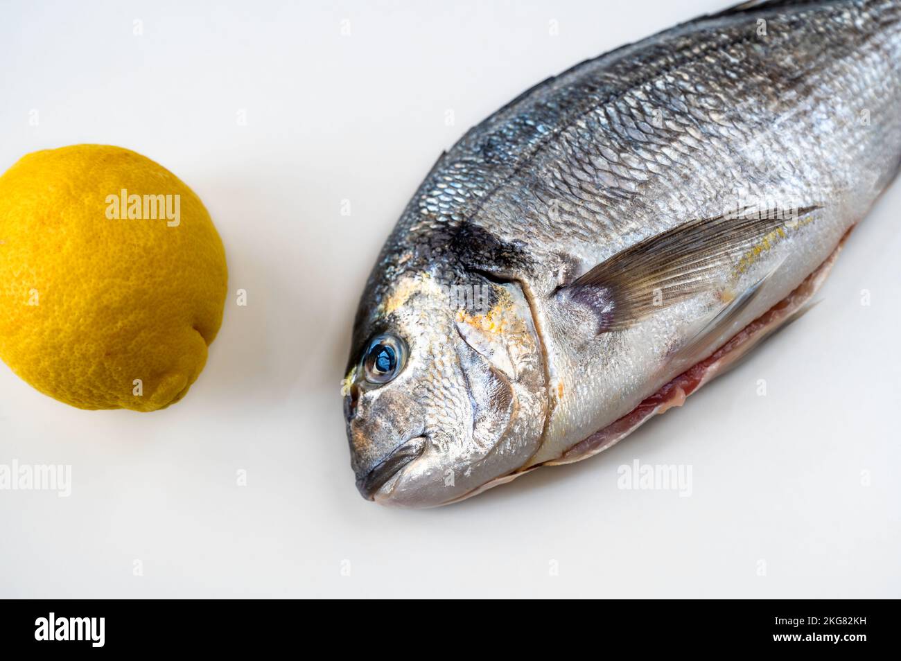 Part of shiny silver body of sea bream ( king bream, dorada), lemon on ...