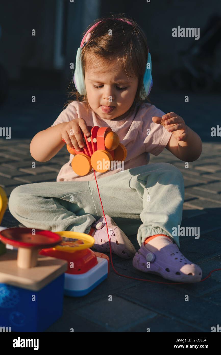 A little girl sitting outdoors, playing as a seller, the child is ...