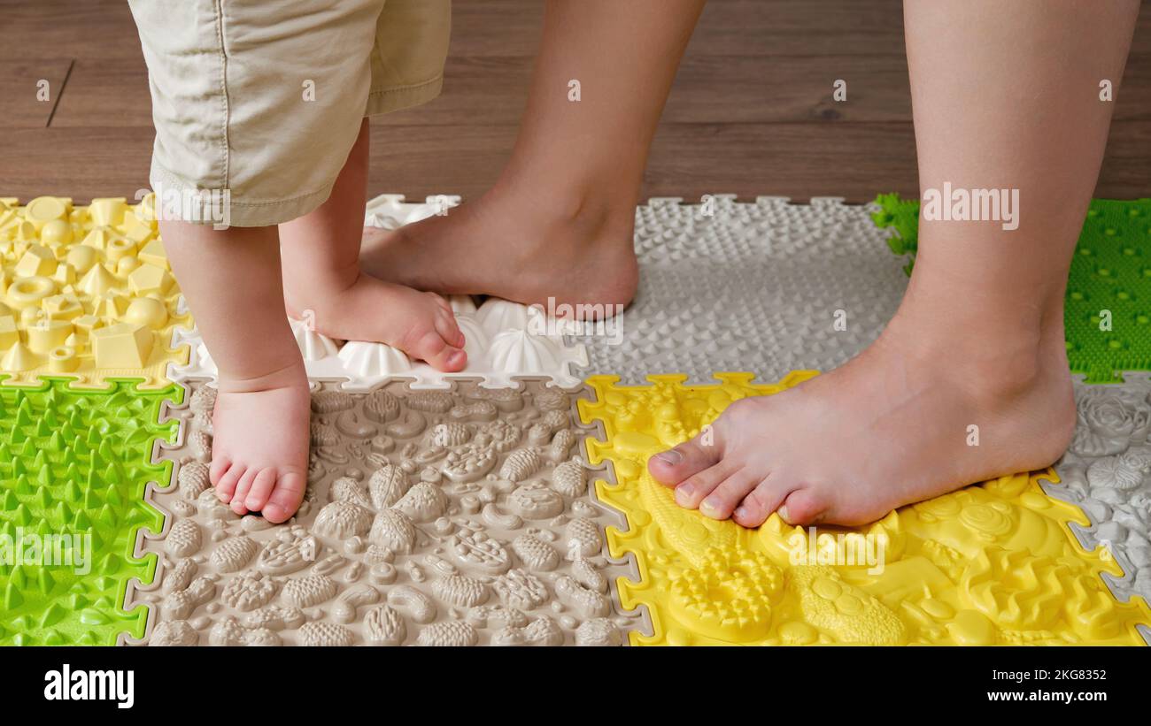 Baby toddler foots and woman mother on a medical orthopedic mat. Child ...