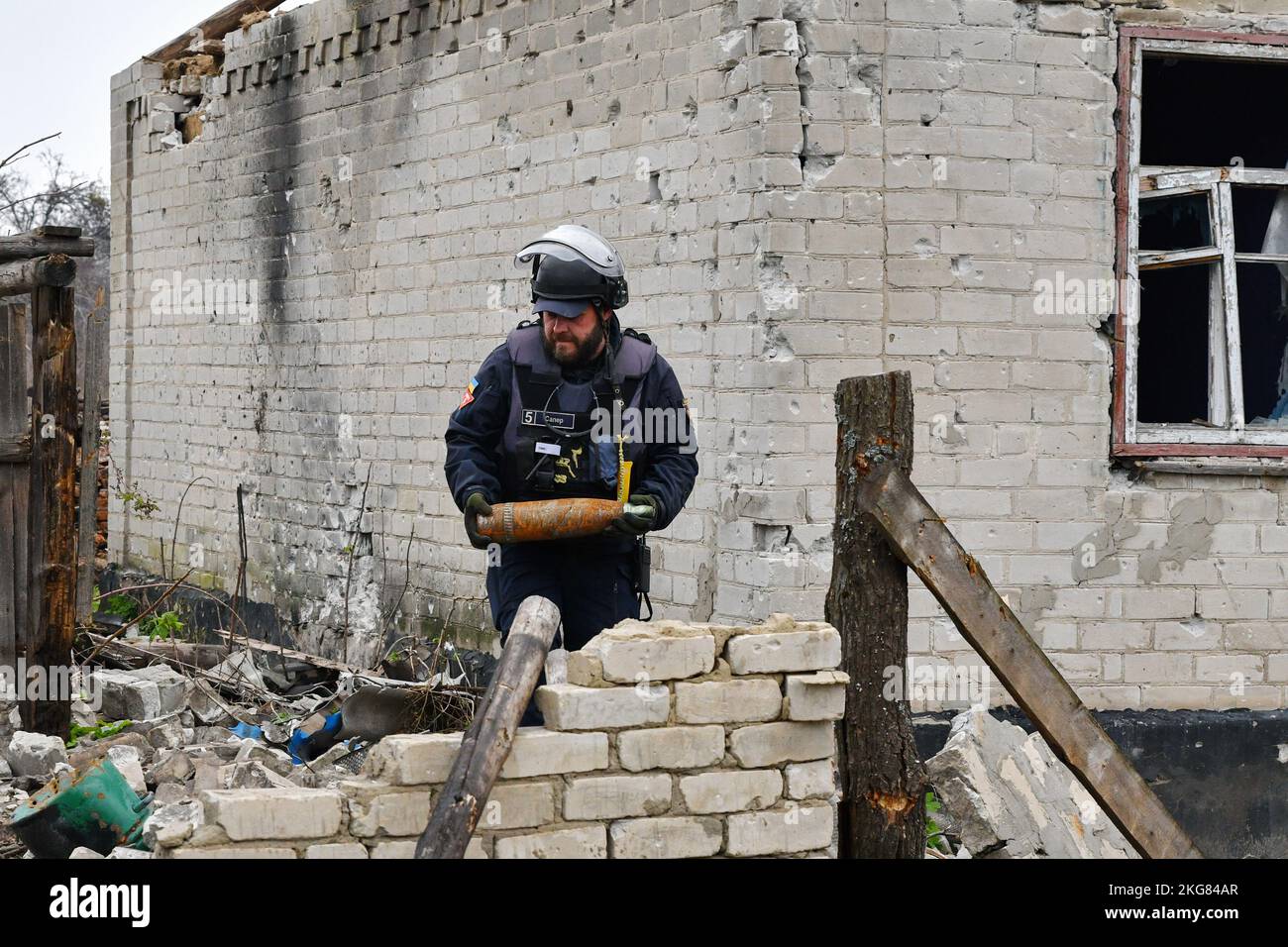 A Ukrainian sapper carries an unexploded shell during a demining ...