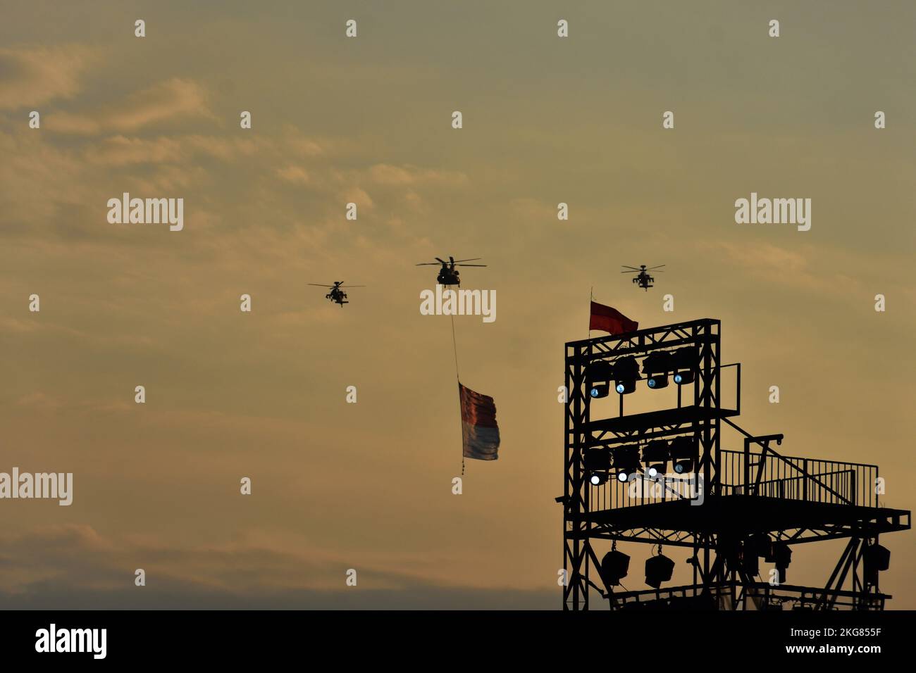 A silhouette of helicopters flying over lighting equipment Stock Photo ...