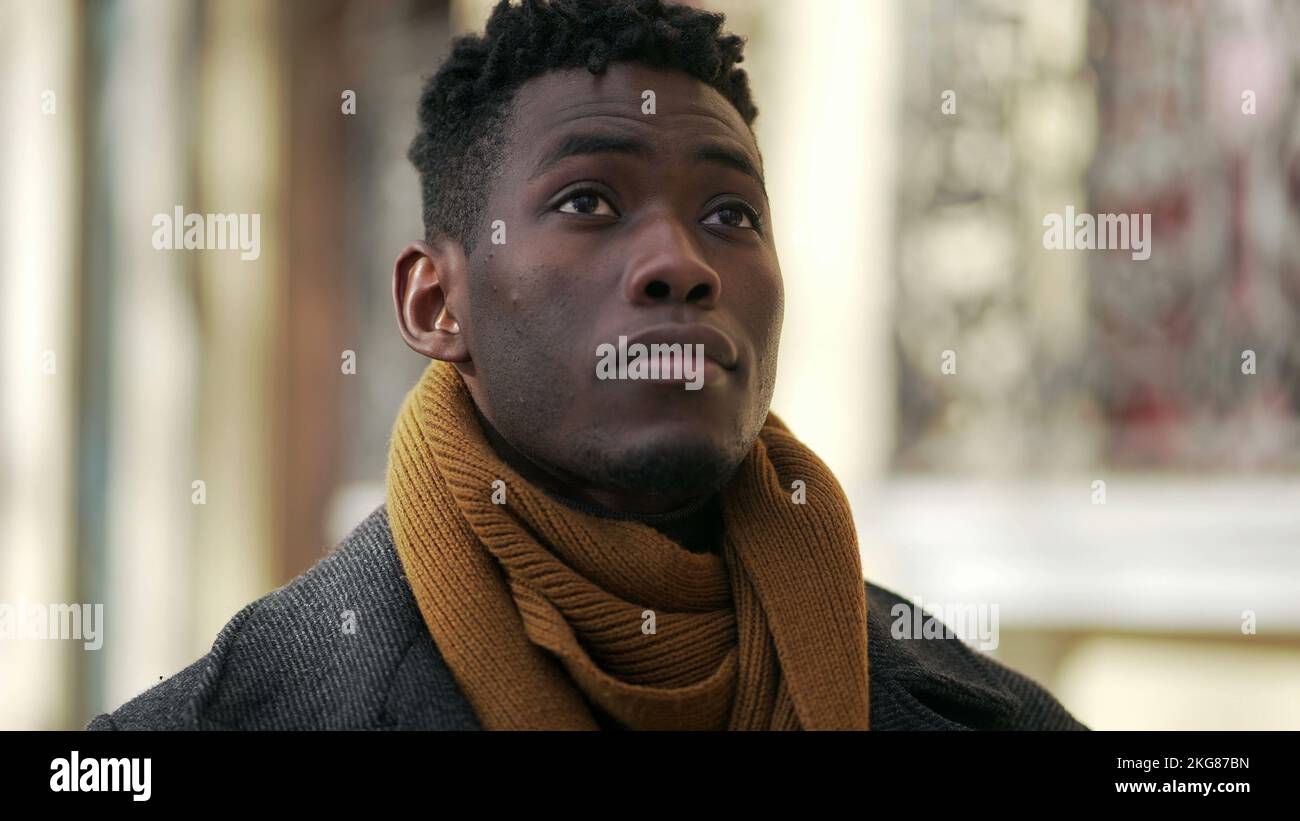Pensive thoughtful black African man standing outside thinking and ...