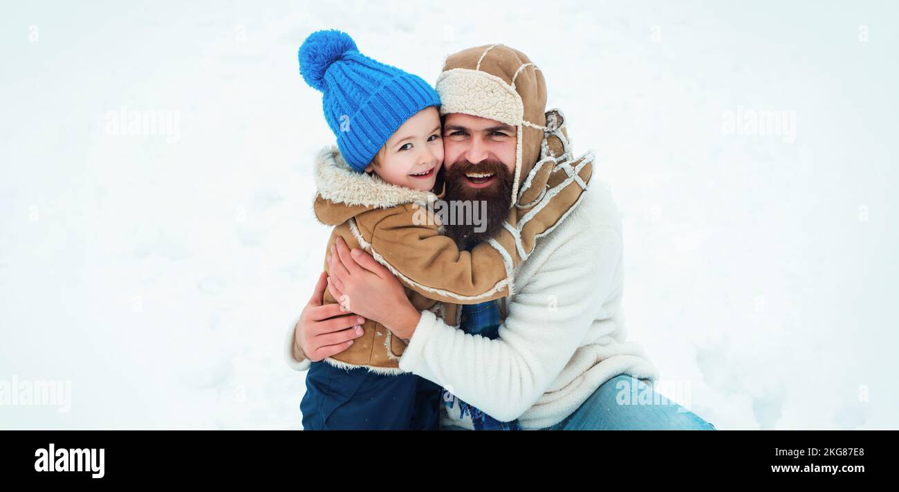 Cute son hugs his dad on winter holiday. Daddy and boy smiling and ...
