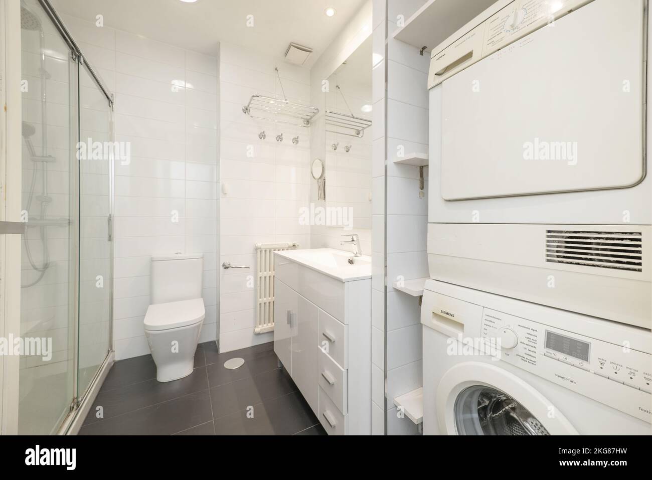 Toilet with white furniture, shower cabin and washing machine and dryer ...