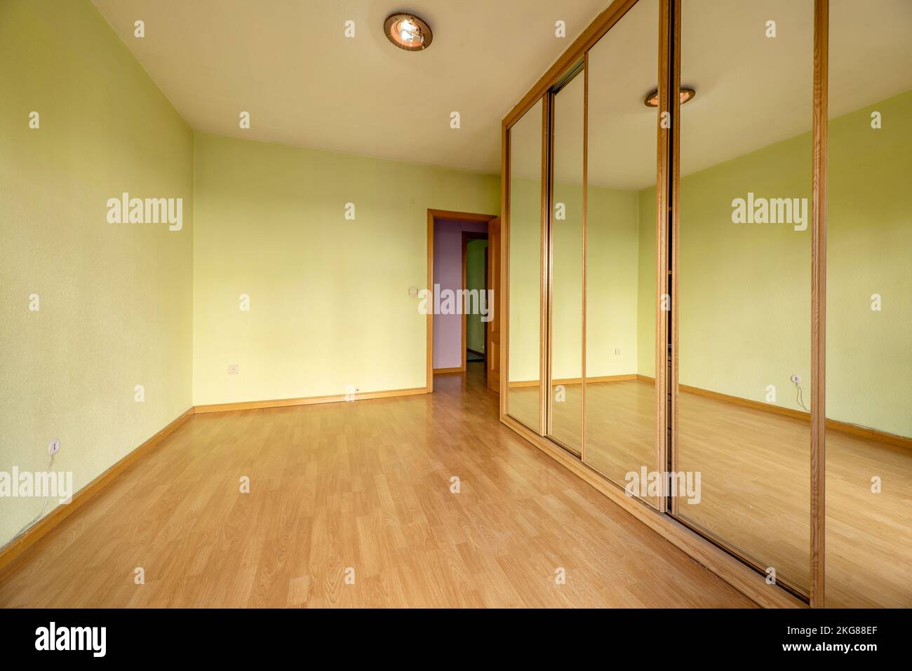 Empty room with laminated flooring and a wall covered with a built-in ...
