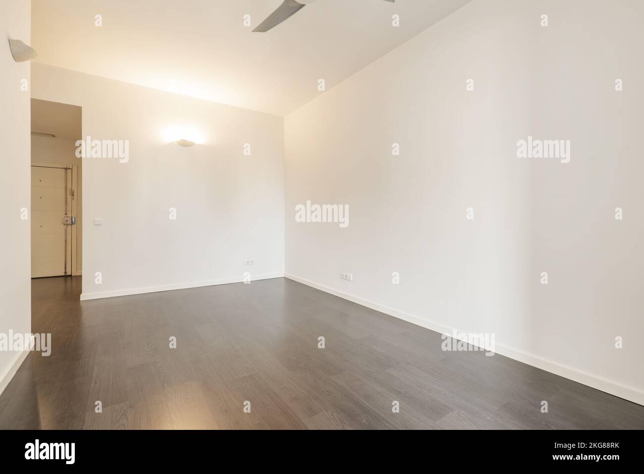 Empty living room with dark laminate flooring and unadorned plain white ...