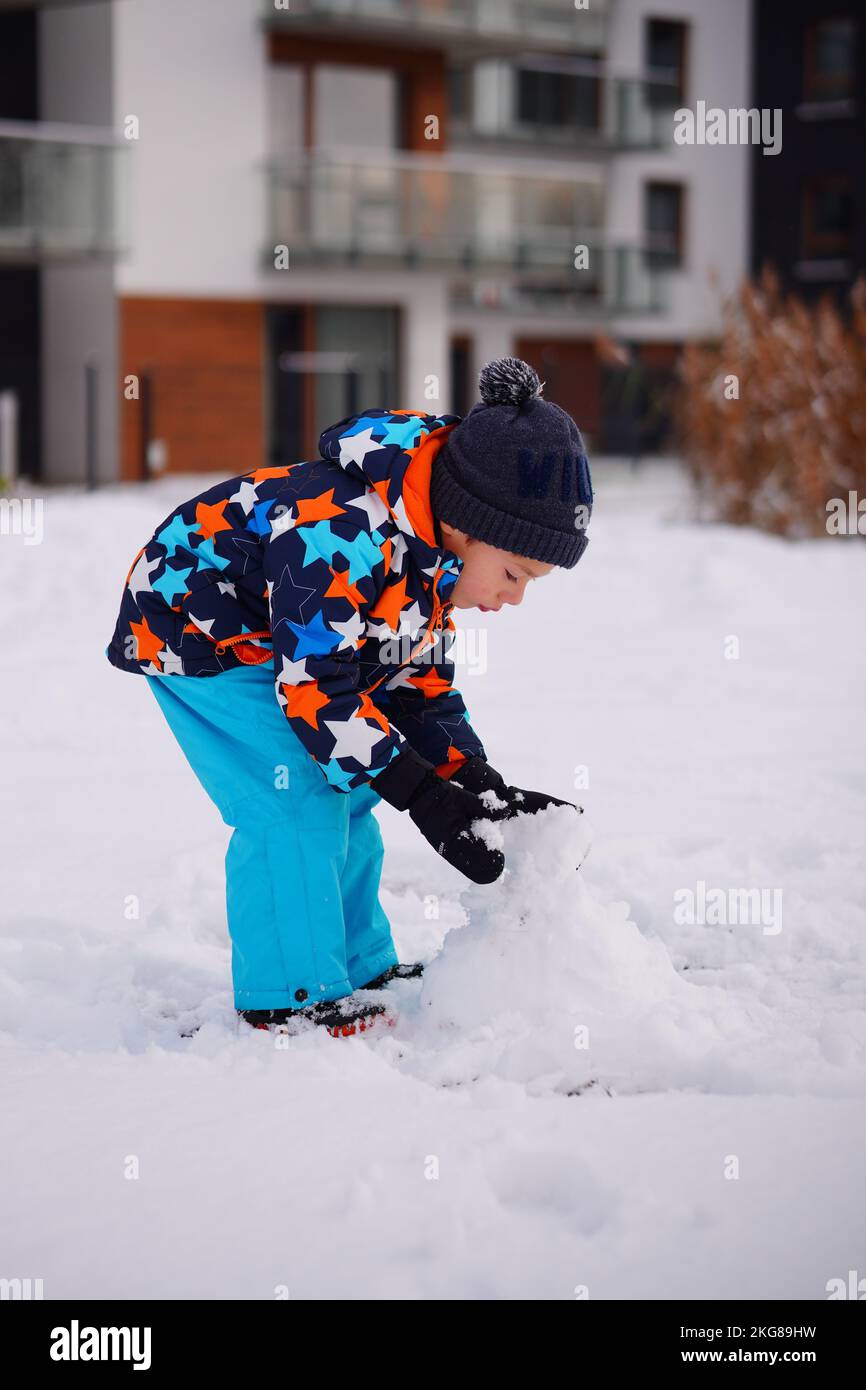 A cute Caucasian kid playing with the snow in the park in winter Stock ...