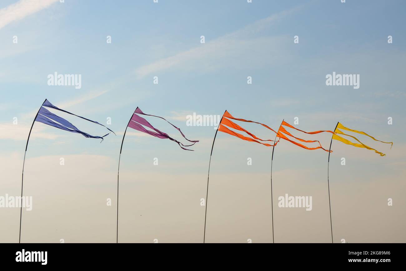 The view of colorful cut flags waving before the shaded sunset sky ...