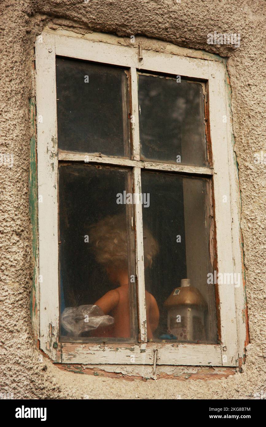 a vintage children's doll in the old window of the house Stock Photo ...