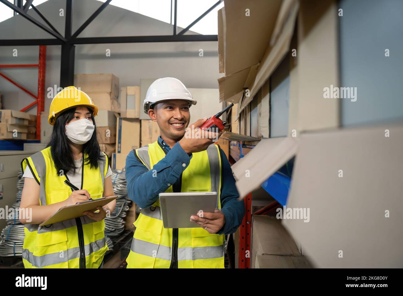 Two smile warehouse workers in uniforms and yellow helmets on heads ...