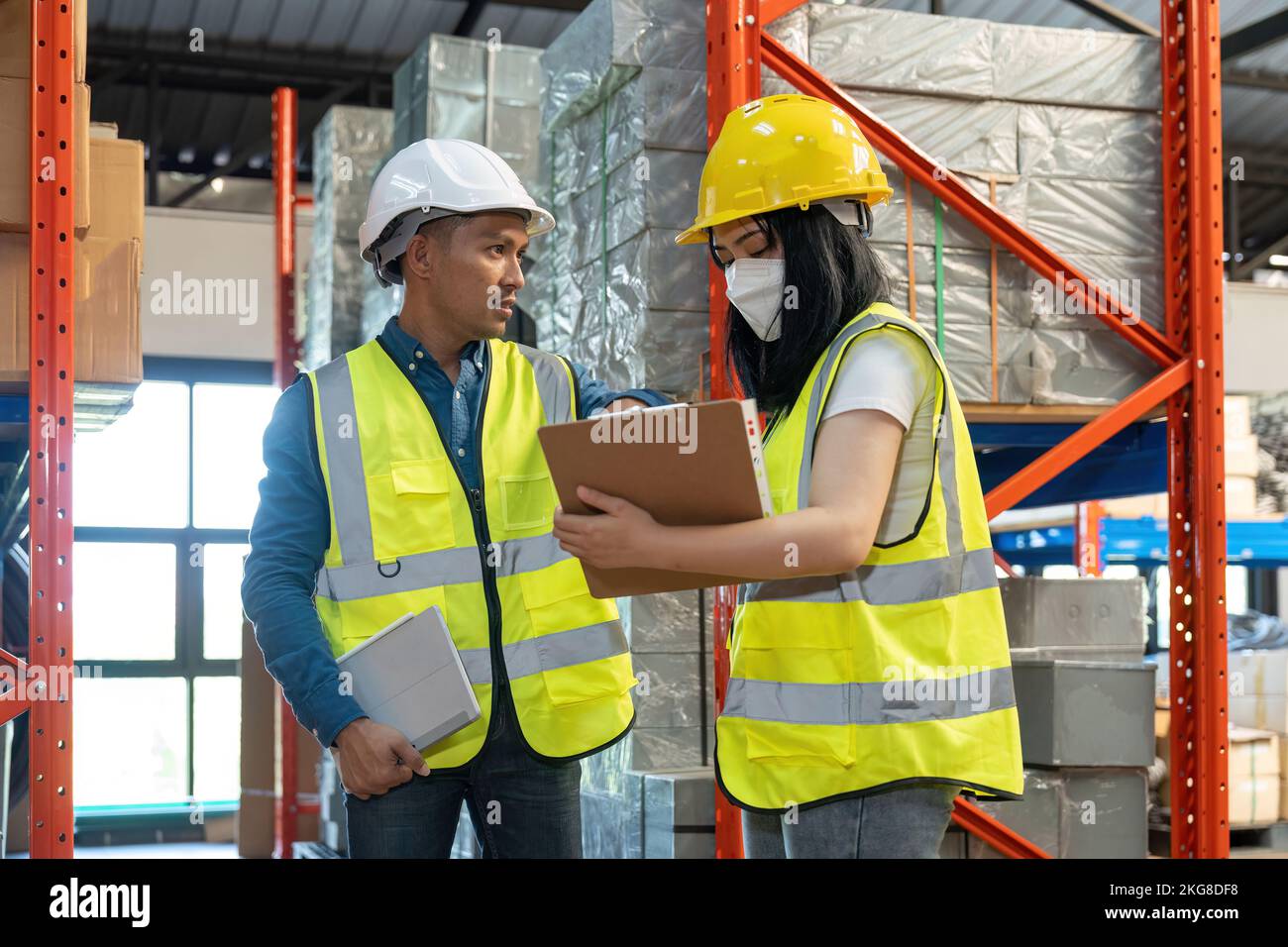 Two smile warehouse workers in uniforms and yellow helmets on heads ...