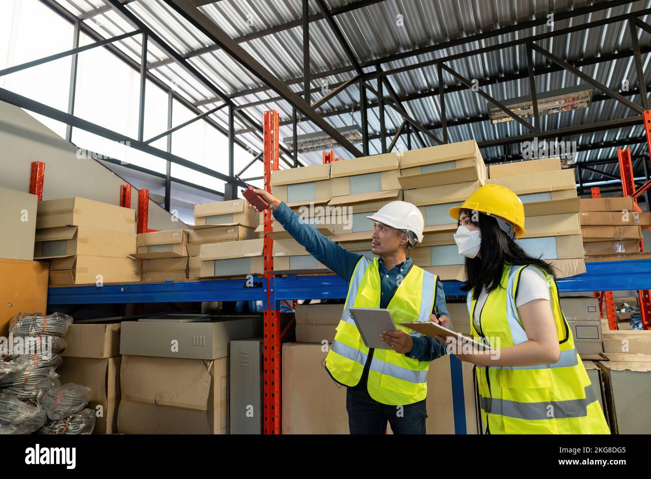 Two smile warehouse workers in uniforms and yellow helmets on heads ...