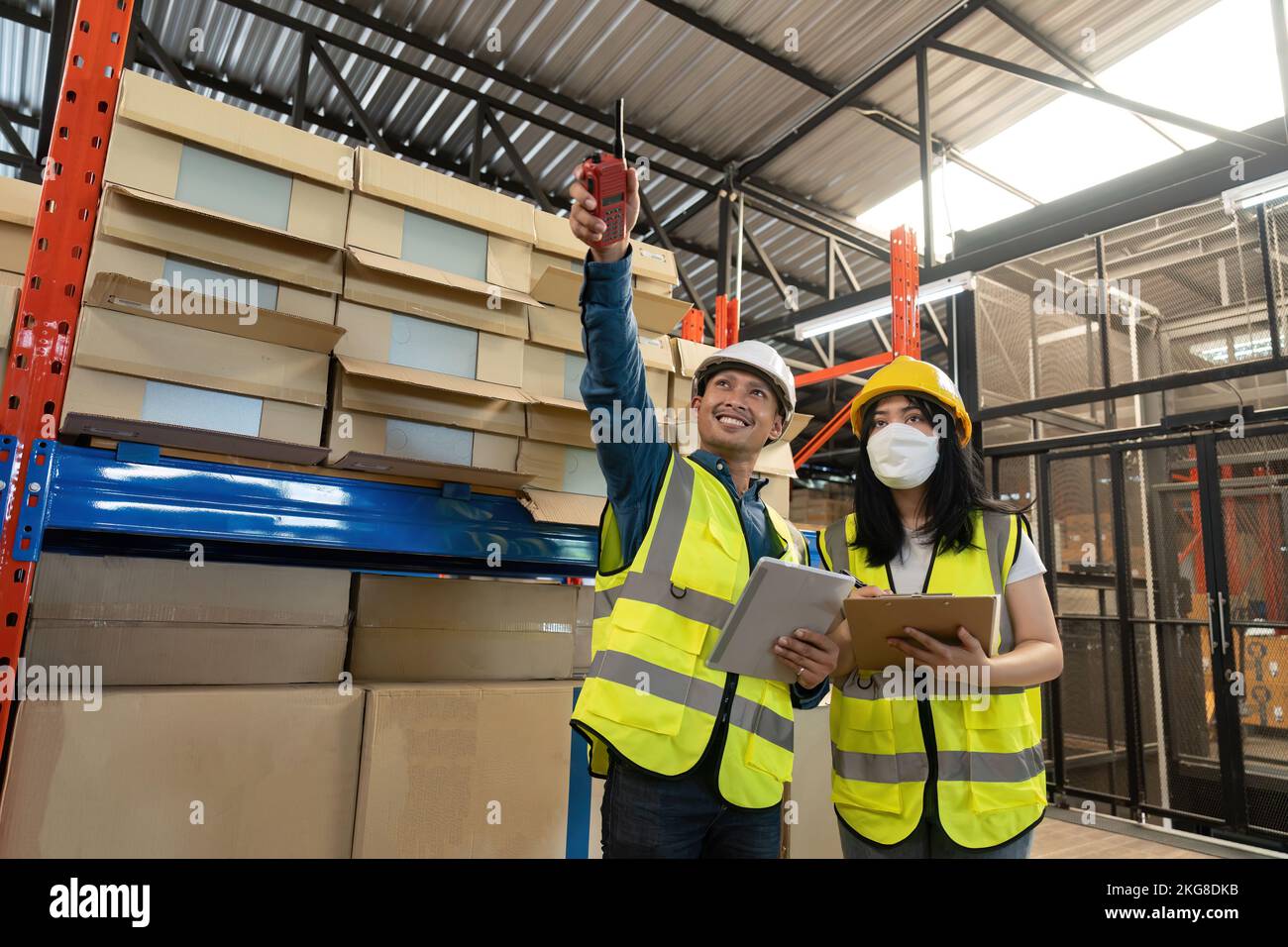 Two smile warehouse workers in uniforms and yellow helmets on heads ...