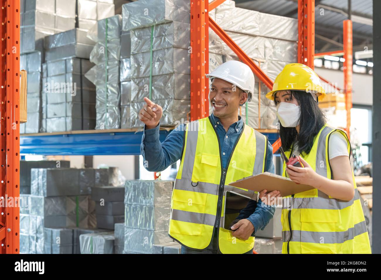 Two smile warehouse workers in white uniforms and yellow helmets on ...