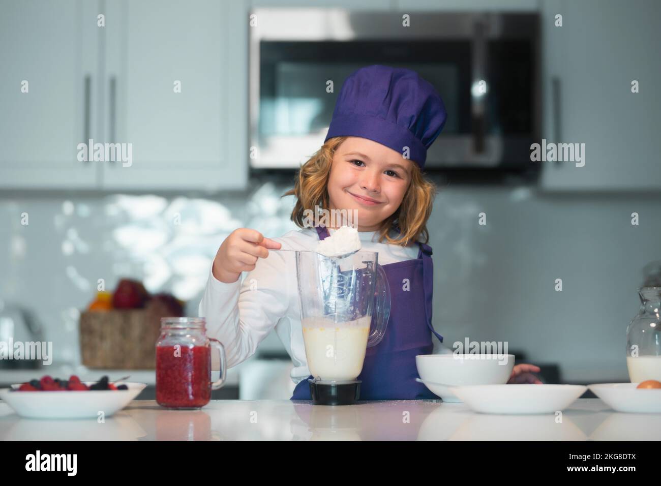 Child chef cooking meal. Chef kid boy in apron and chef hat cooking at ...